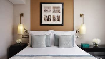 Quarto de hotel com uma cama grande, duas mesas de cabeceira, uma fotografia emoldurada na parede e duas luminárias fixadas na parede.