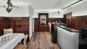 Uma cozinha moderna com painéis de madeira, uma ilha central e um espaço de refeições com uma mesa posta para quatro pessoas.