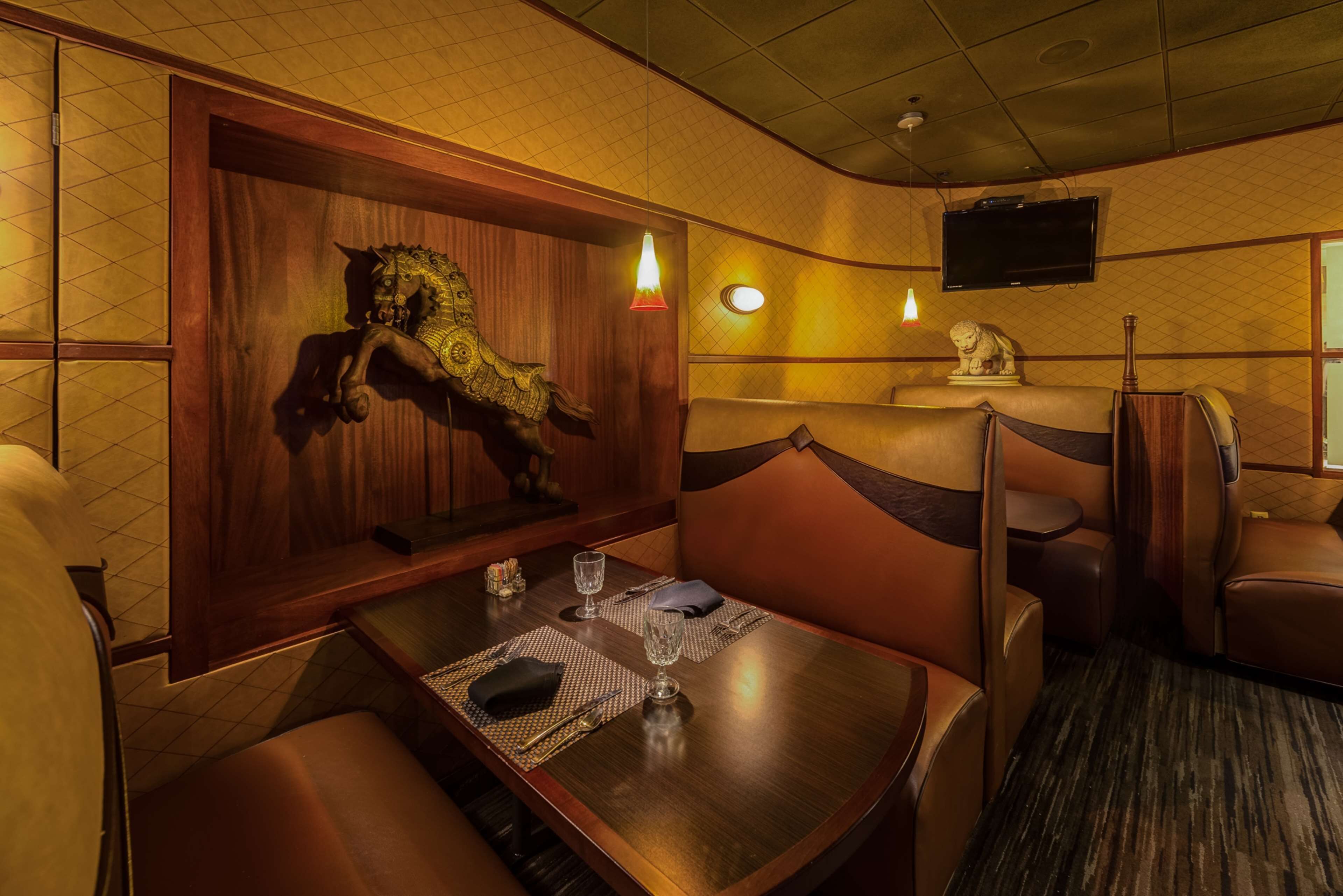 Um restaurante com parede de madeira, uma escultura de cavalo montado e uma televisão.