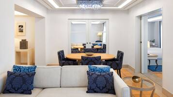 Quarto de hotel moderno com sofá, mesa de jantar redonda e lustre.