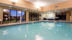 Piscina interior com escorrega, espreguiçadeiras e área de estar com sofás.