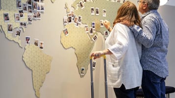 Um casal em frente a uma parede com um mapa e fotos fixadas.