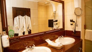Uma casa de banho de hotel com duas pias, um espelho grande, um secador de cabelo e um porta-toalhas.