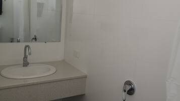 Casa de banho com uma pia branca, um espelho e uma porta de chuveiro.