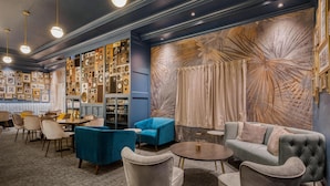 Uma área de lounge moderna com assentos confortáveis, uma parede decorada com equipamentos de áudio antigos e um mural ornamental.