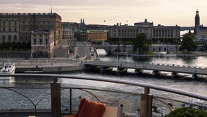 Vista para o rio, com uma ponte, edifícios históricos e um cais para barcos.