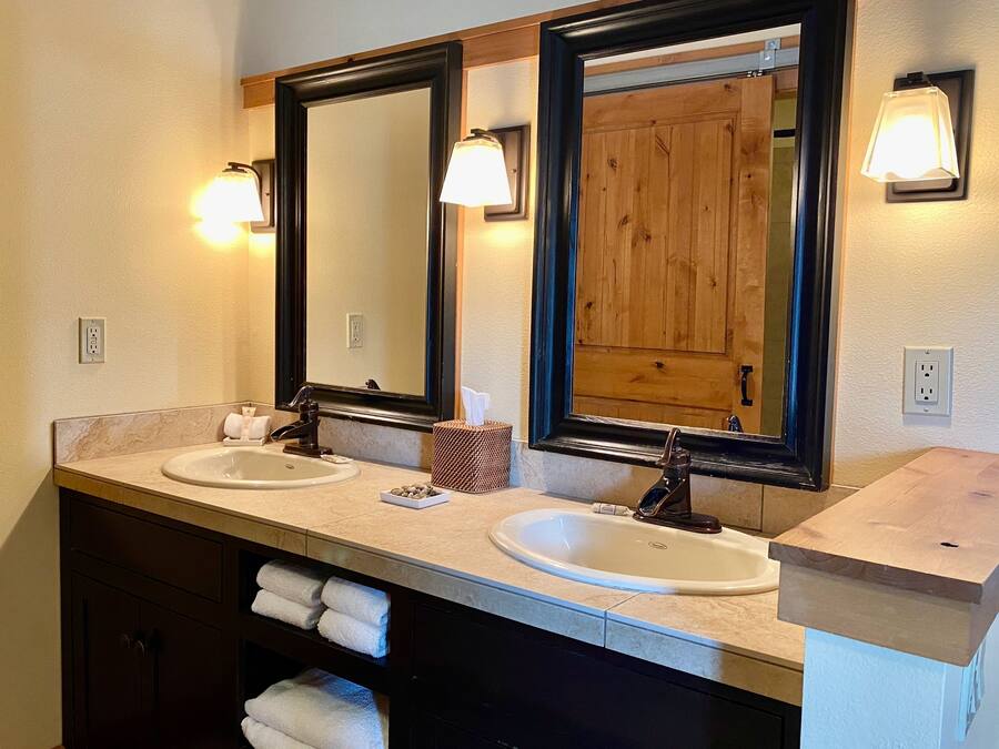 Casa de banho com duas pias, um espelho e um porta-toalhas.