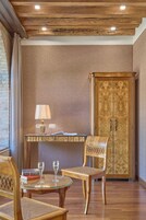 Um quarto com uma mesa de madeira, duas cadeiras, um abajur e um armário.