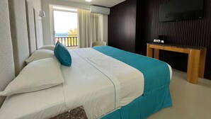 Quarto de hotel com cama, televisão e varanda.