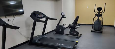 Uma academia com esteiras, elípticos e bicicleta ergométrica.
