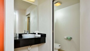Casa de banho com lavatório de bancada preta, espelho e sanita.