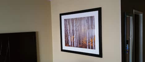 Quadro com uma imagem de bétulas em uma parede em um quarto.