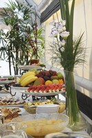 Uma mesa de buffet com diversas frutas, legumes e doces.