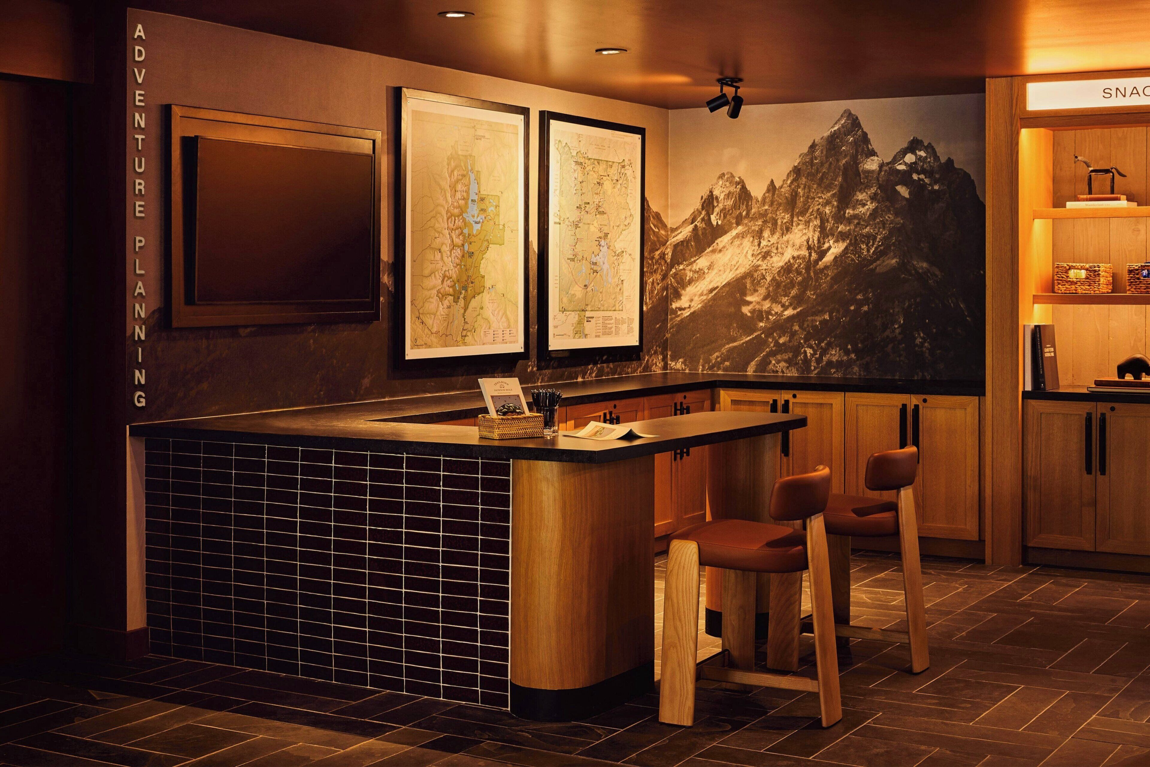 Uma área de bar com balcão de madeira, banquetas e um mapa grande na parede.