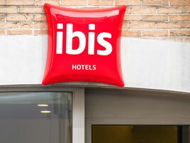 Uma placa vermelha com a palavra 'ibis' e 'HOTEIS', indicando o nome do hotel.