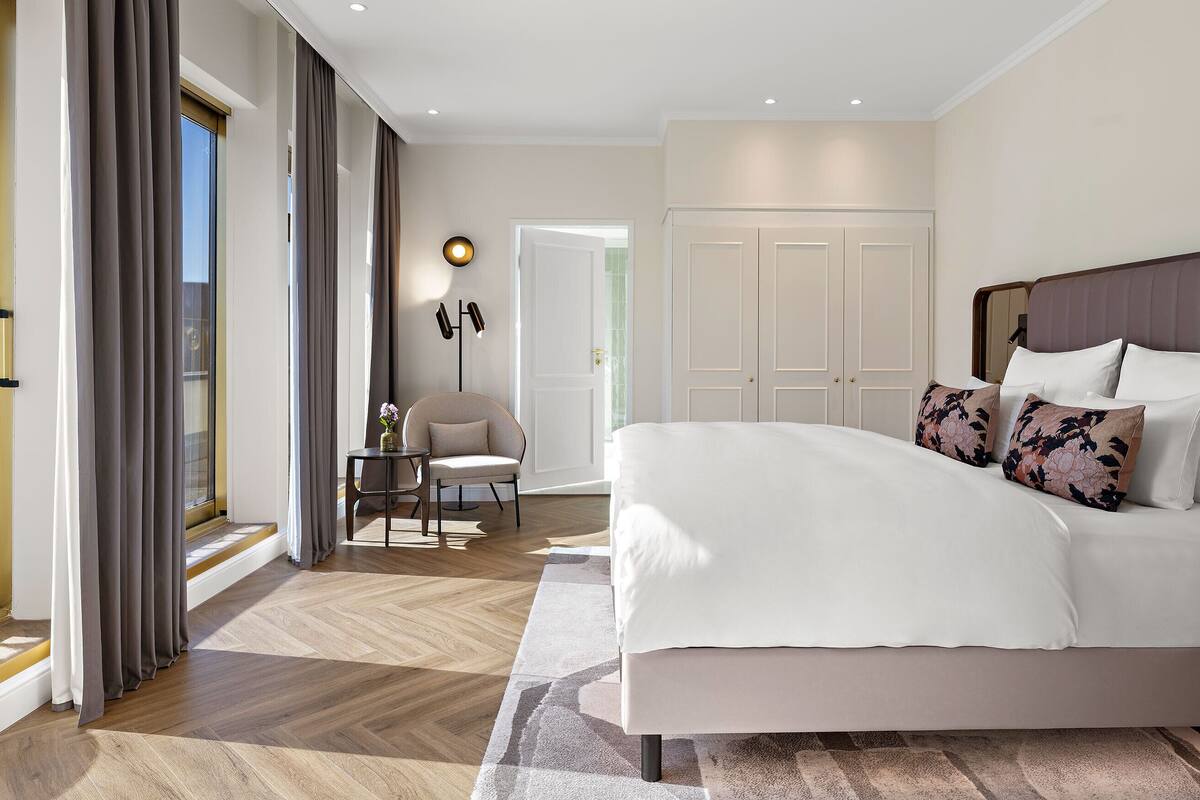 Um quarto moderno com uma cama grande, uma cadeira, uma escrivaninha e vista para o exterior.