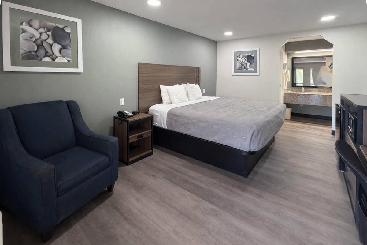 Quarto com cama, mesa de cabeceira, cadeira e cômoda.
