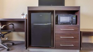 Uma cozinha compacta equipada com geladeira, micro-ondas e um pequeno armário com gavetas.