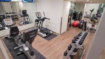 Uma academia com equipamentos de cardio, bancos de peso e bolas de exercícios.