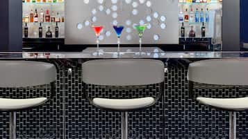 Uma área de bar com três banquetas e uma parede com padrão hexagonal.