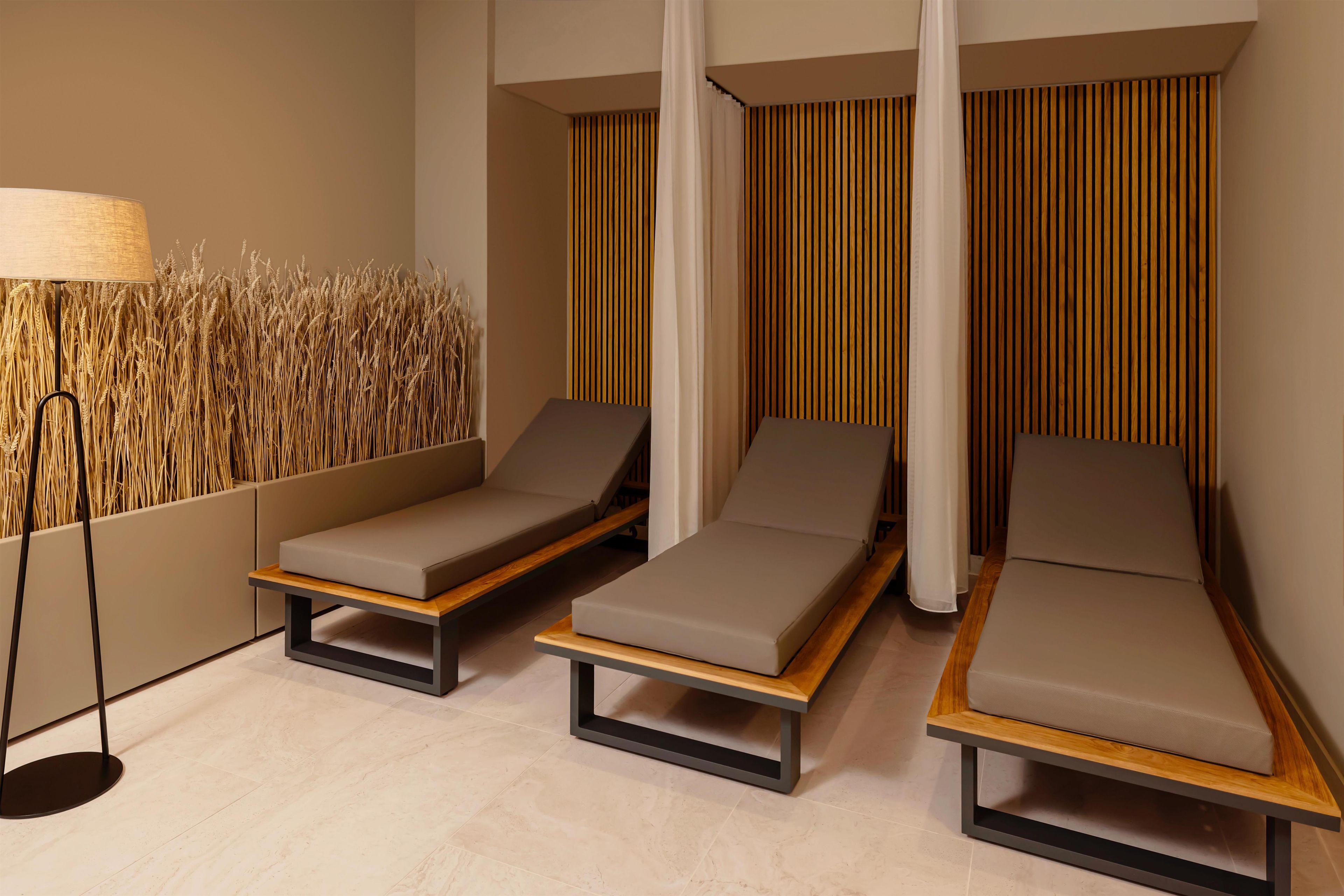 Um espaço de spa com três poltronas confortáveis, um abajur e uma parede com ripas de madeira verticais.