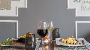 Uma mesa de jantar com velas, copos de vinho e pratos de comida.