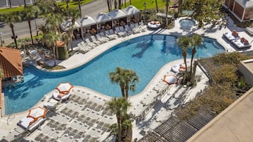 Área de piscina em resort, com espreguiçadeiras, hidromassagem e espaço para relaxamento.
