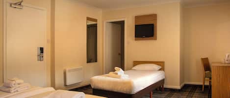 Quarto de hotel com duas camas, uma escrivaninha, uma cadeira, uma televisão e um espelho.