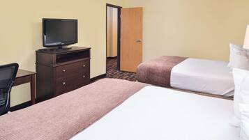Quarto de hotel com uma cama, uma escrivaninha com televisão, cómoda e porta para outro espaço.