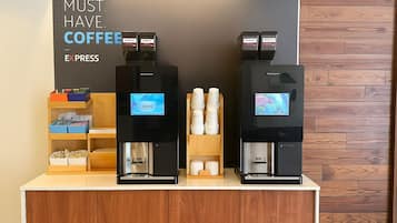 Estação de café com duas máquinas de expresso, um dispensador de café e um aviso que diz 'MUST. HAVE. COFFEE'.