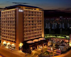 Um hotel com vários andares e um destaque para o letreiro 'Divan', apresentando um design arquitetônico moderno com uma grade de janelas e um telhado plano.
