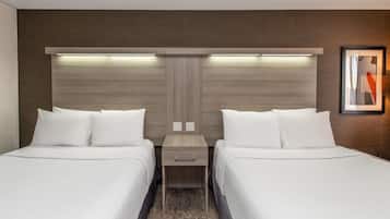 Quarto de hotel com duas camas, uma mesa de cabeceira e um quadro pendurado na parede.