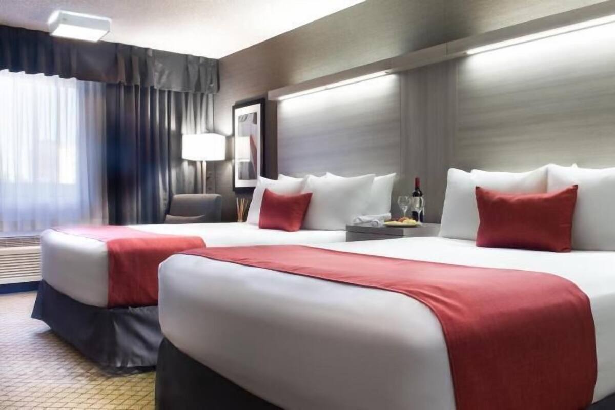 Quarto de hotel com duas camas, uma mesa e uma cadeira.