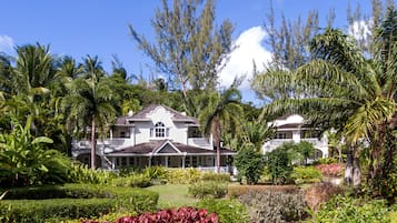 Uma grande casa de estilo colonial, com uma varanda espaçosa e um jardim bem cuidado.