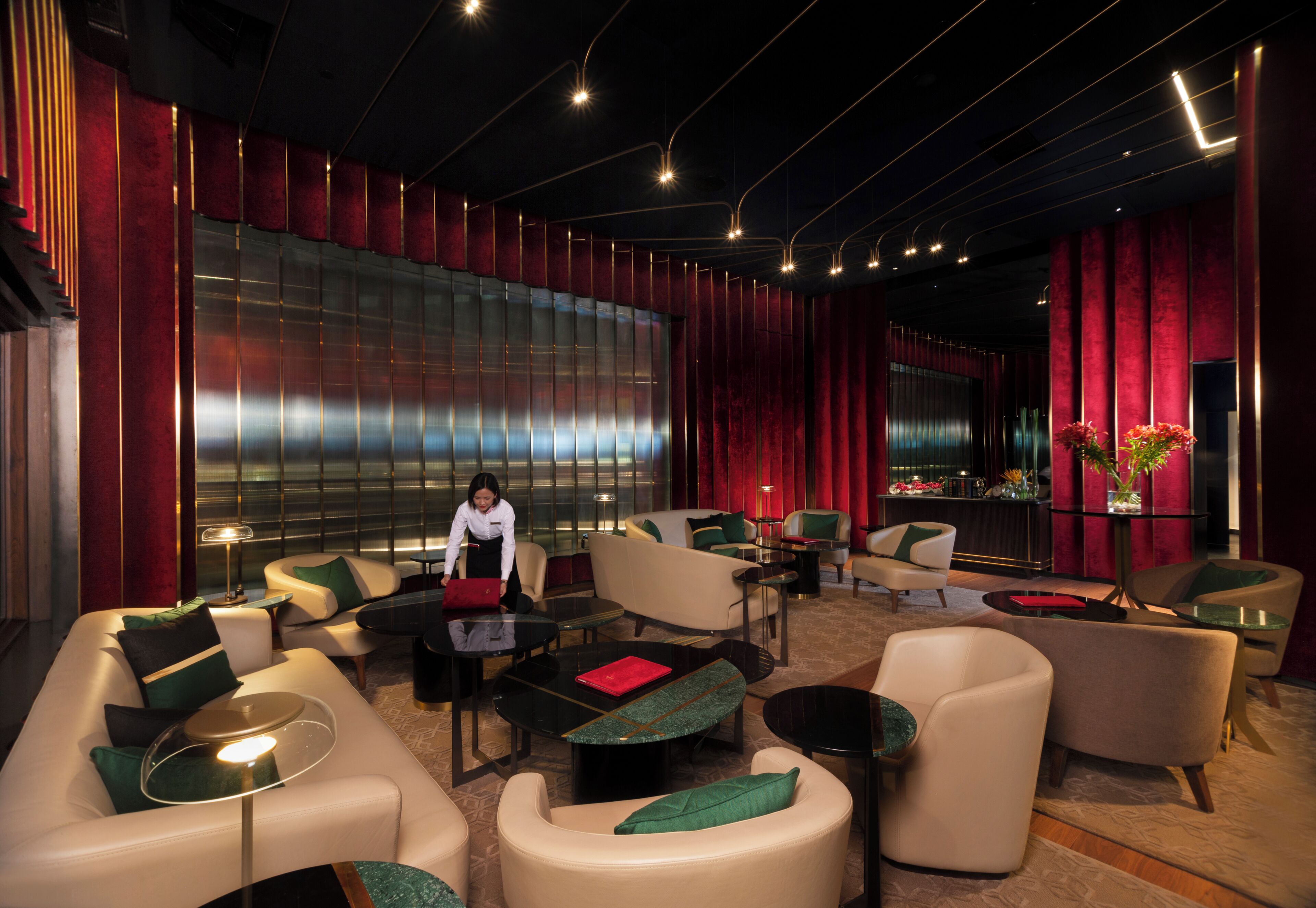 Um lobby de hotel moderno com sofás de couro, mesas redondas e um bar.