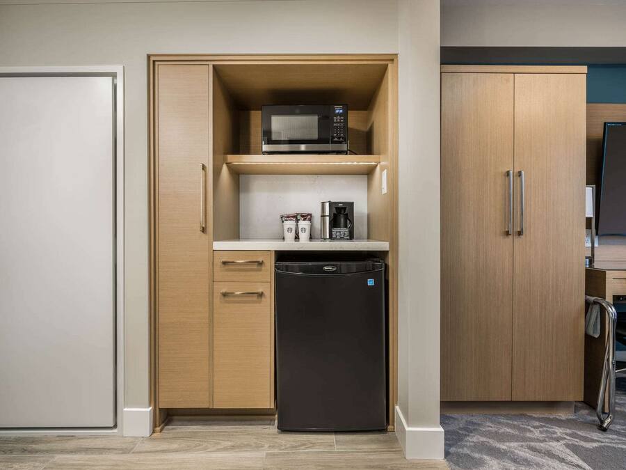 Uma cozinha compacta equipada com micro-ondas, máquina de café e lava-louças.