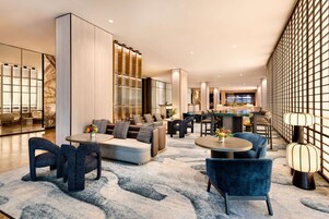 Um saguão de hotel moderno com área de estar, bar e uma grande janela com padrão de grade.