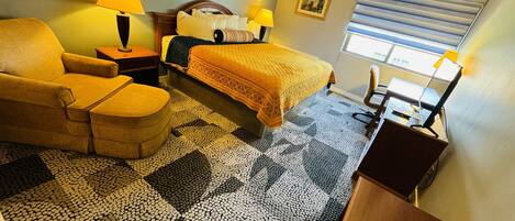 Quarto de hotel com cama, sofá, escrivaninha e cadeira.