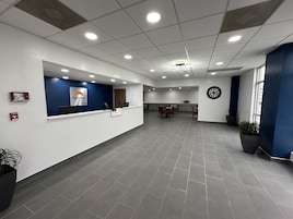 Uma área de recepção ampla com uma parede azul decorativa, um relógio e um balcão de atendimento.