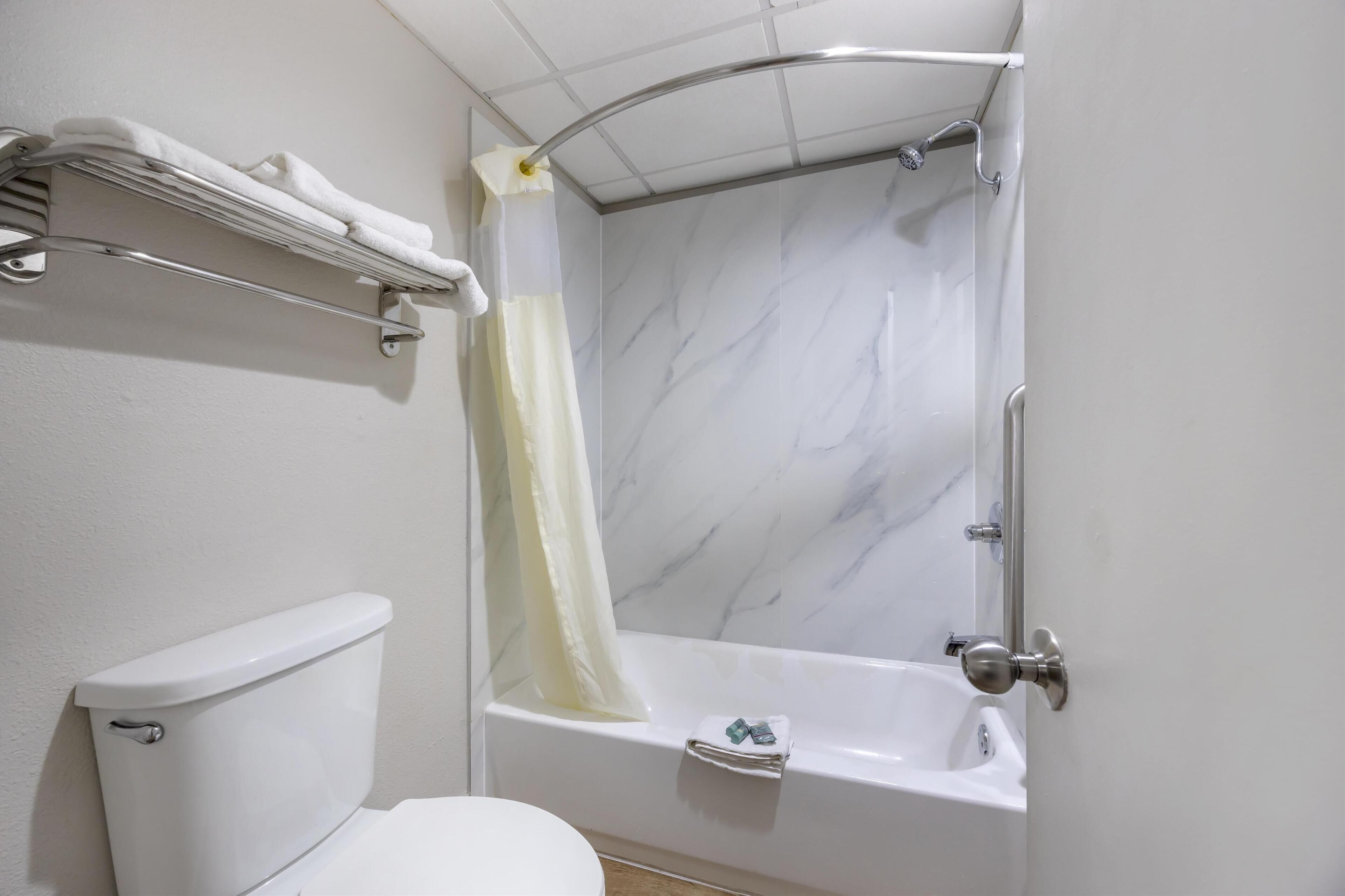 Um banheiro com vaso sanitário, chuveiro com porta de vidro e porta-toalhas.