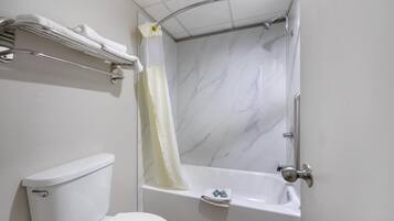 Um banheiro com vaso sanitário, chuveiro com porta de vidro e porta-toalhas.