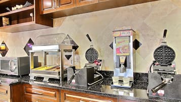 Disposição de buffet com micro-ondas, máquina de waffles e estação para waffles.