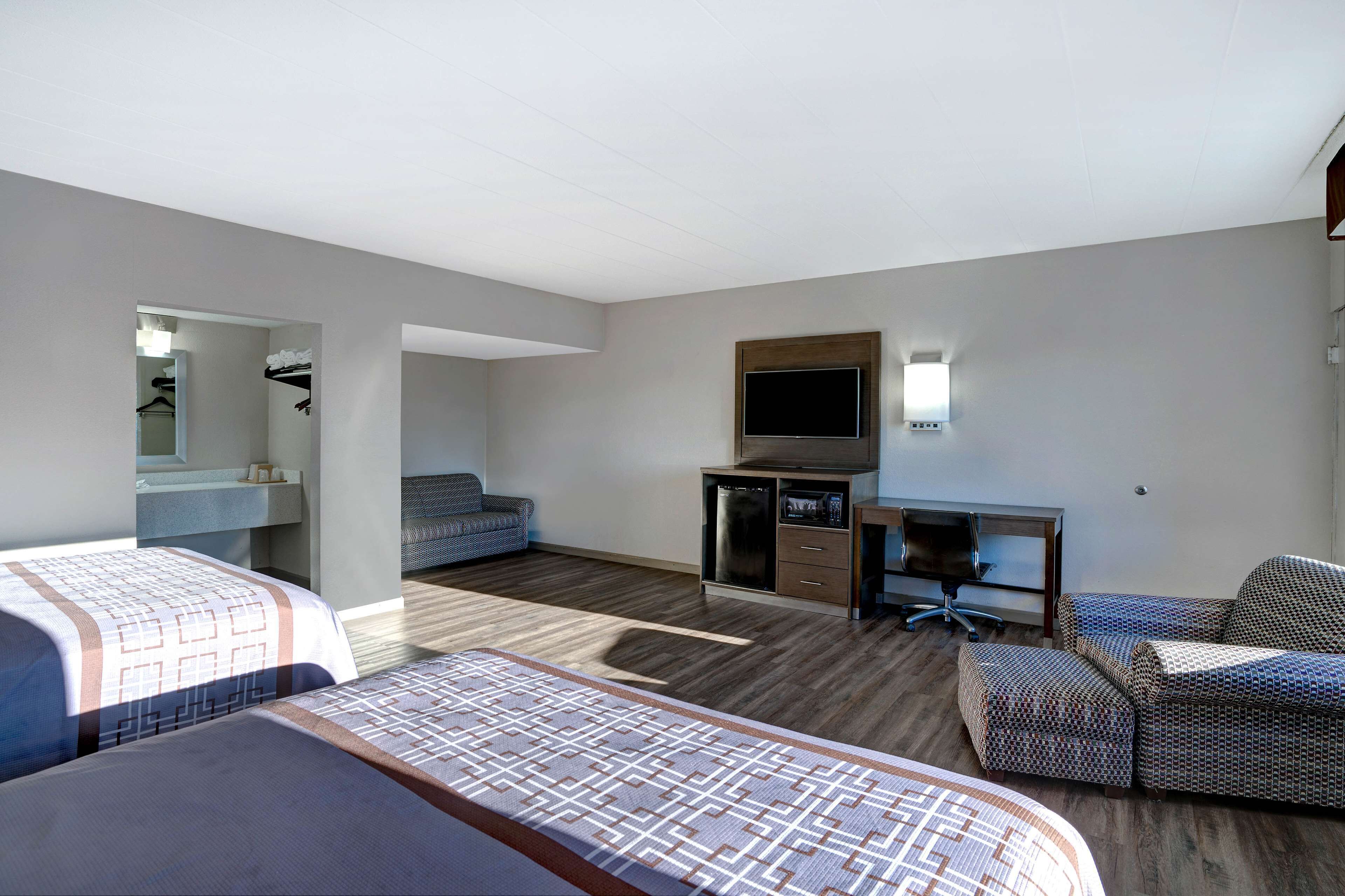 Quarto de hotel com duas camas, uma mesa, uma televisão e uma cadeira.