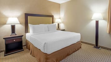 Quarto de hotel com uma cama grande, duas mesas de cabeceira e duas luminárias.