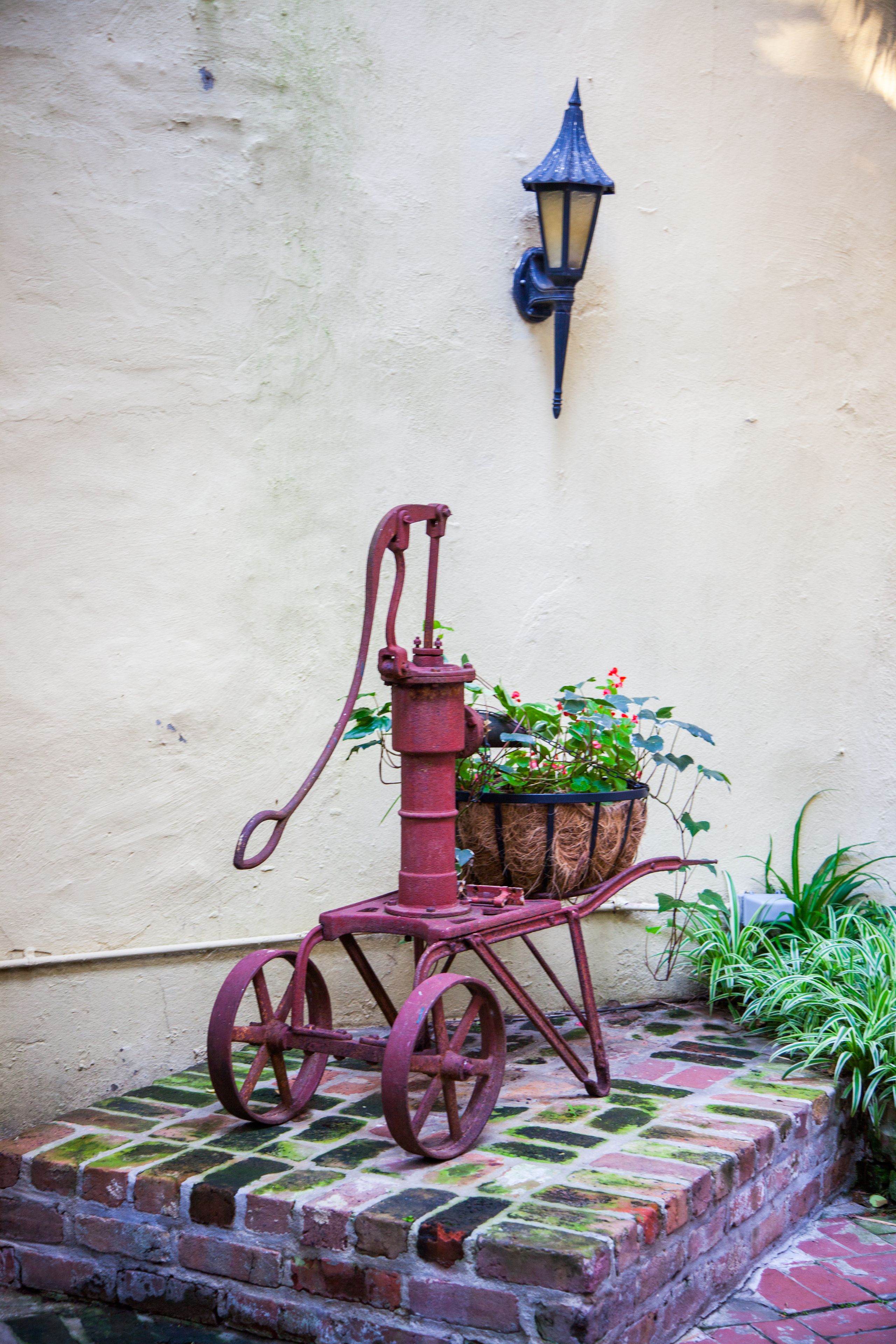 Uma bicicleta vermelha antiga com um cesto de plantas em frente a uma parede.