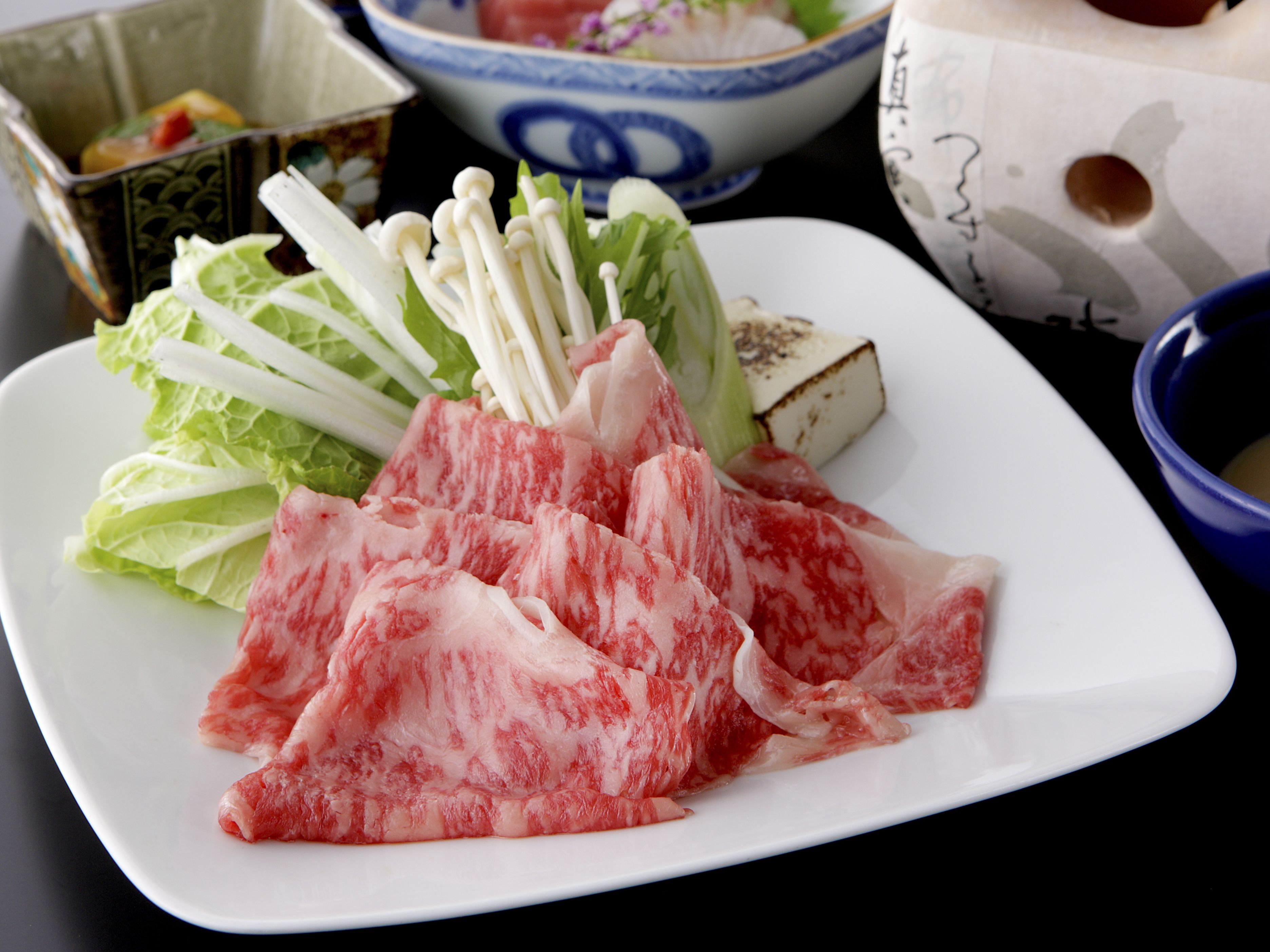 Um prato com carne crua, vegetais e cogumelos.