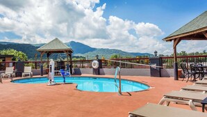 Piscina no terraço com espreguiçadeiras e um gazebo, cercada por montanhas.