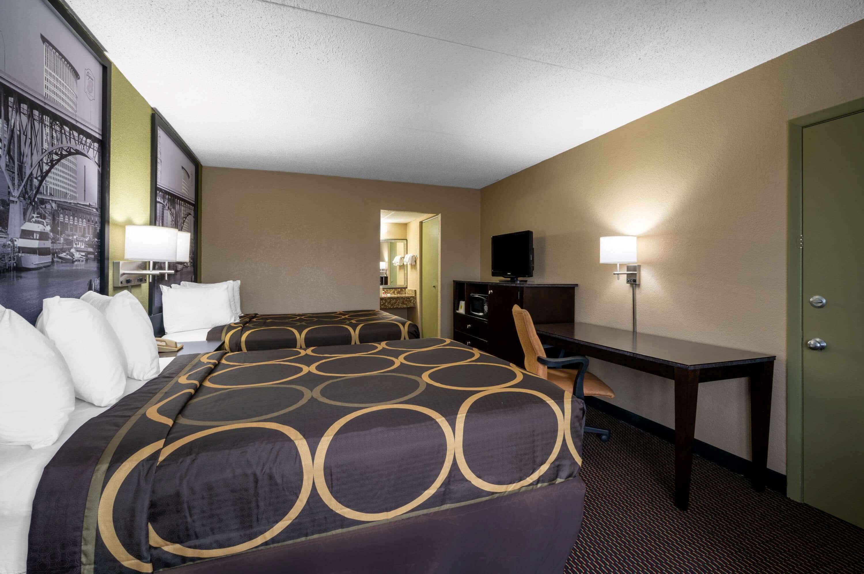 Quarto de hotel com cama grande, escrivaninha, televisão e porta.