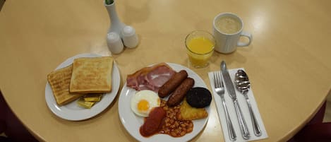 Um prato de pequeno-almoço com torradas, ovos, salsichas, feijão e morcela.