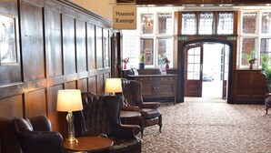 Um hall com carpete estampado, poltronas de couro, um candelabro e uma placa com a inscrição 'Discount Lounge'.